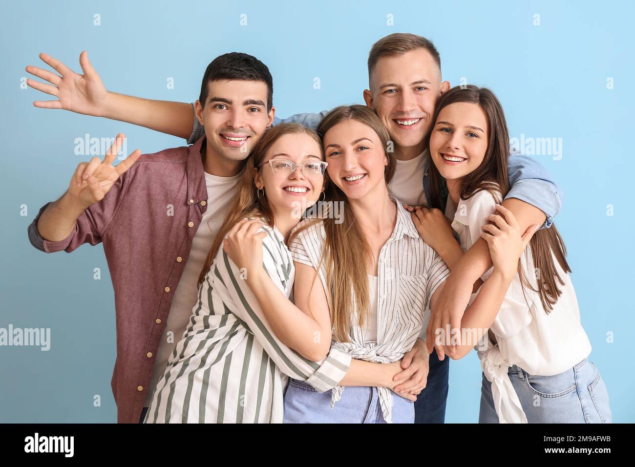 Group of happy friends hugging on blue background Stock Photo - Alamy