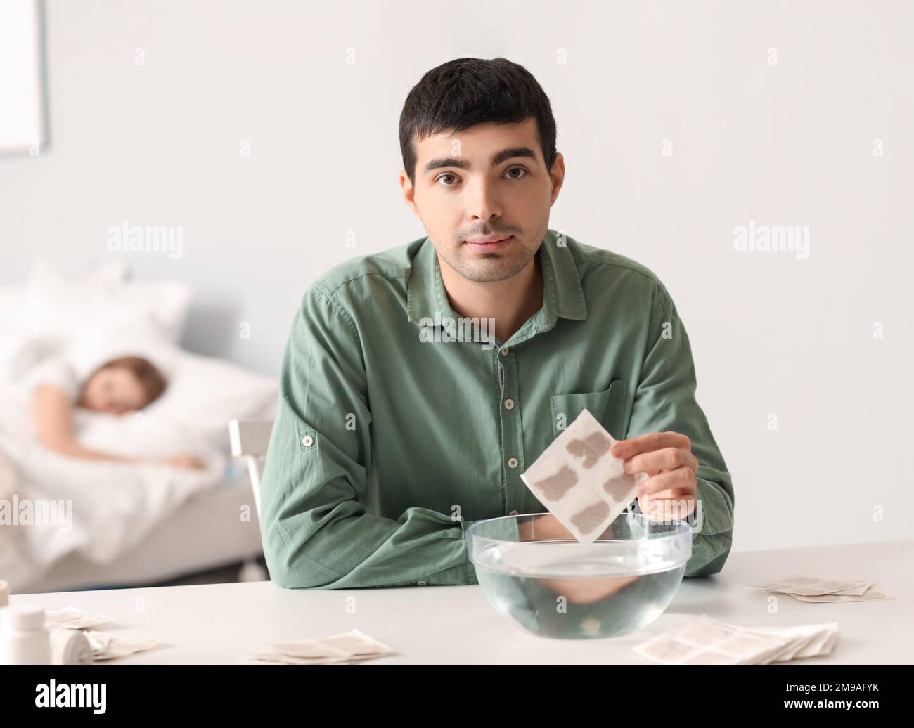 Young man dipping mustard plaster into bowl of water in bedroom Stock ...