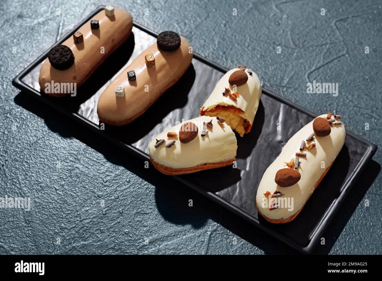 Board with delicious eclairs on dark background Stock Photo - Alamy