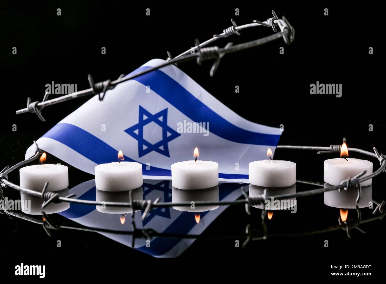 Burning candles, flag of Israel and barbed wire on dark background ...