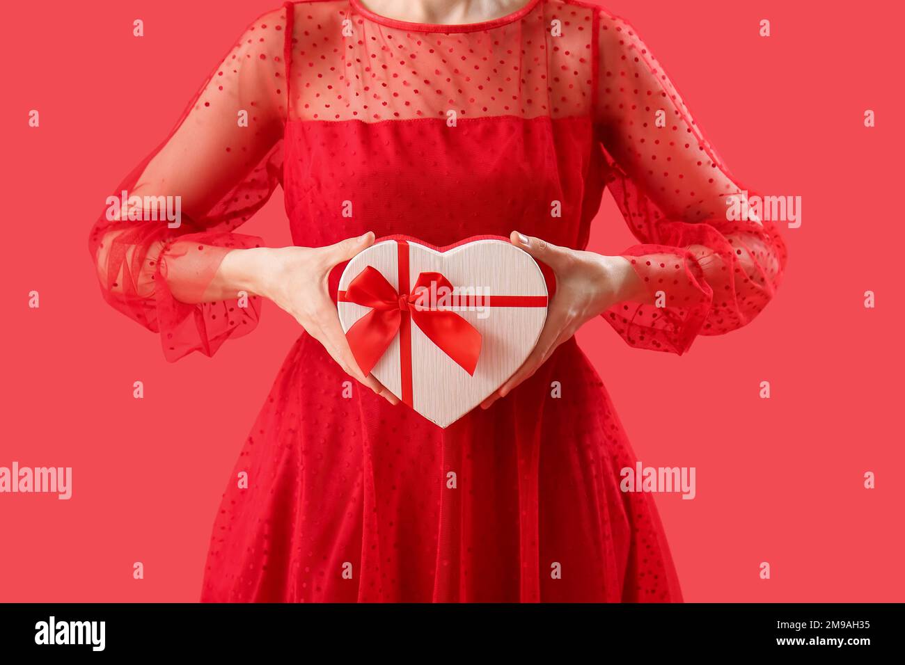 Woman in dress with gift box for Valentine's Day on red background ...