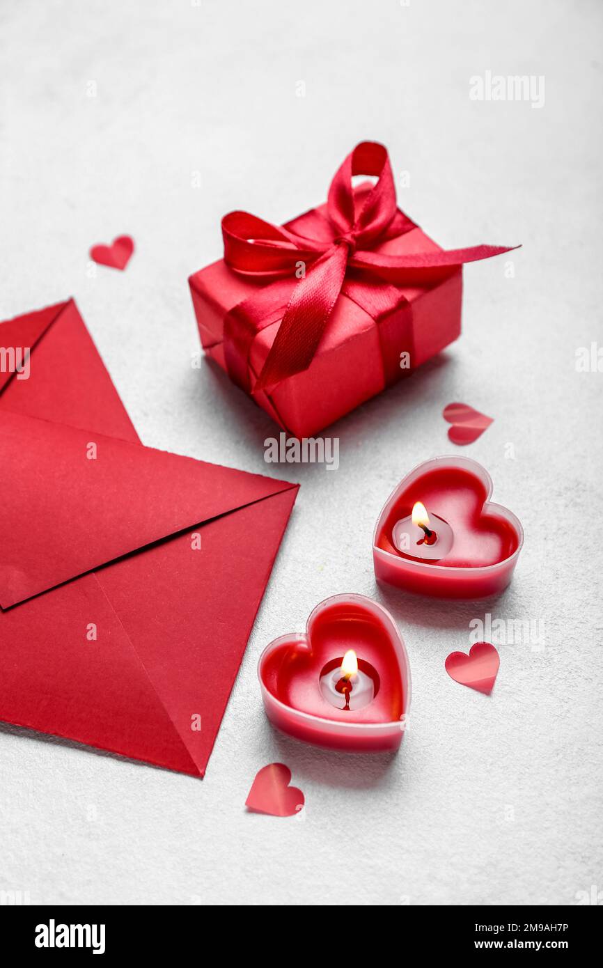 Composition with burning candles, gift box and envelopes on light ...