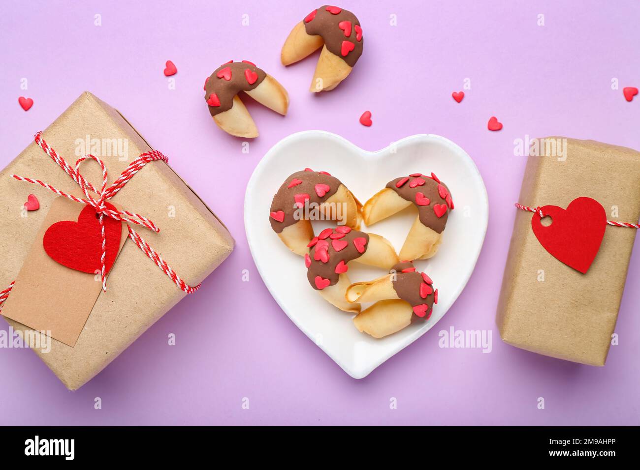 Composition with plate of tasty fortune cookies and gift boxes on lilac ...
