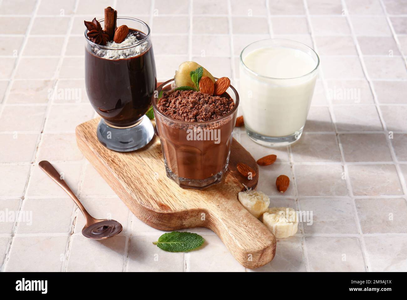 Board with glasses of delicious chocolate pudding, cinnamon, almond and ...