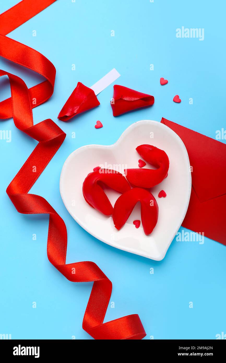 Plate of fortune cookies with envelope and ribbon on blue background ...