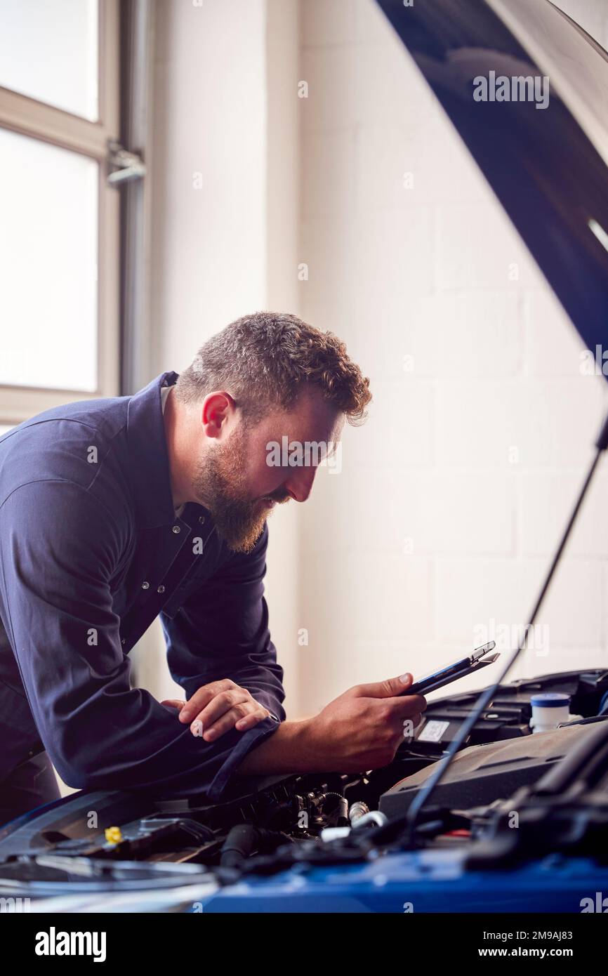 Male Mechanic In Garage Using Diagnostic Software On Digital Tablet To ...