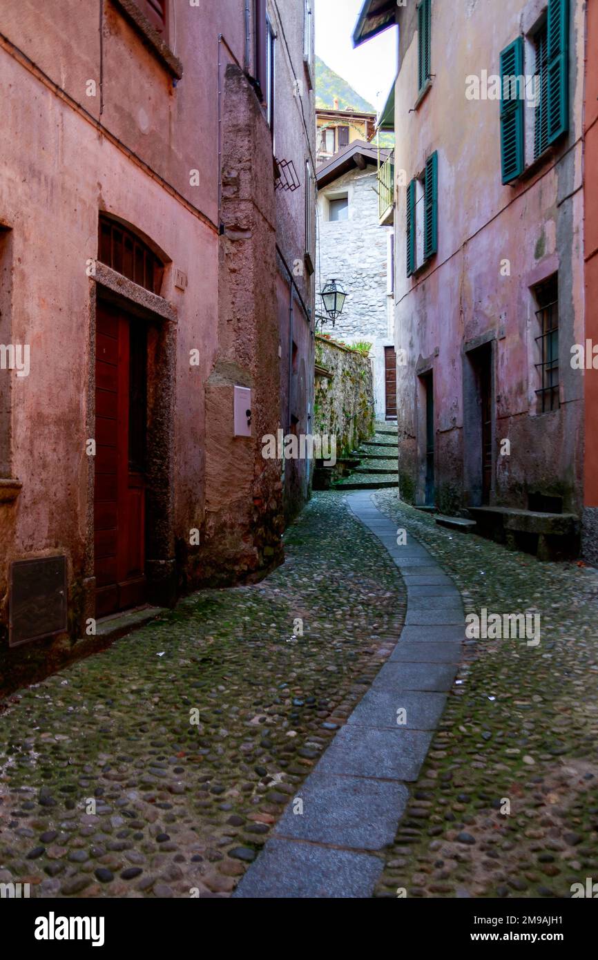 A vertical shot of a narrow alley between buildings in Argegno Italy ...
