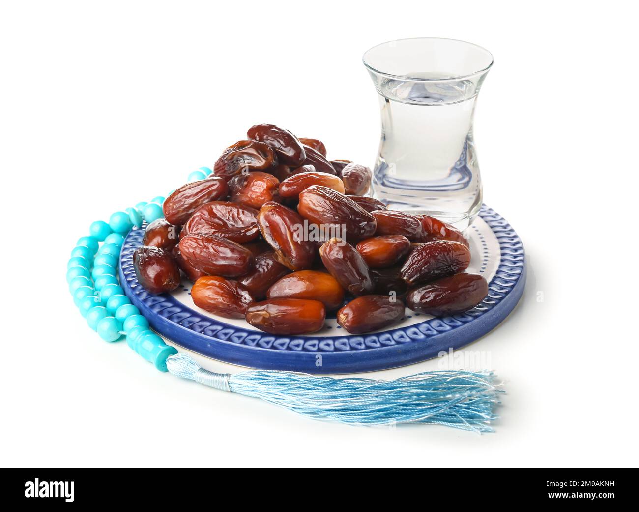 Plate with dried dates, glass of water and prayer beads for Ramadan on ...