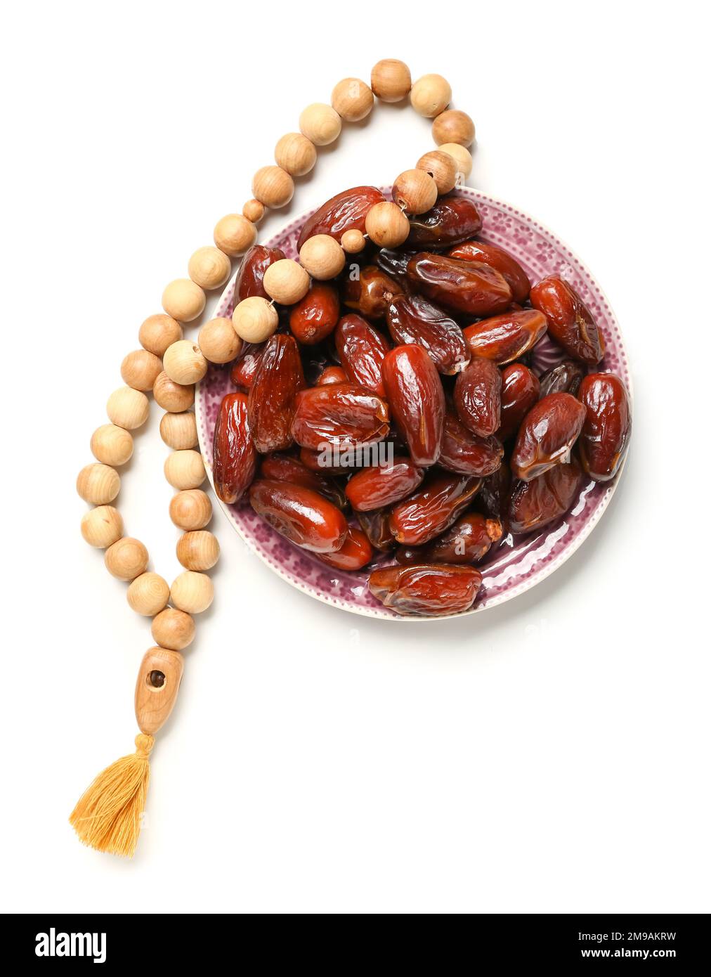Plate with dried dates and prayer beads for Ramadan on white background ...