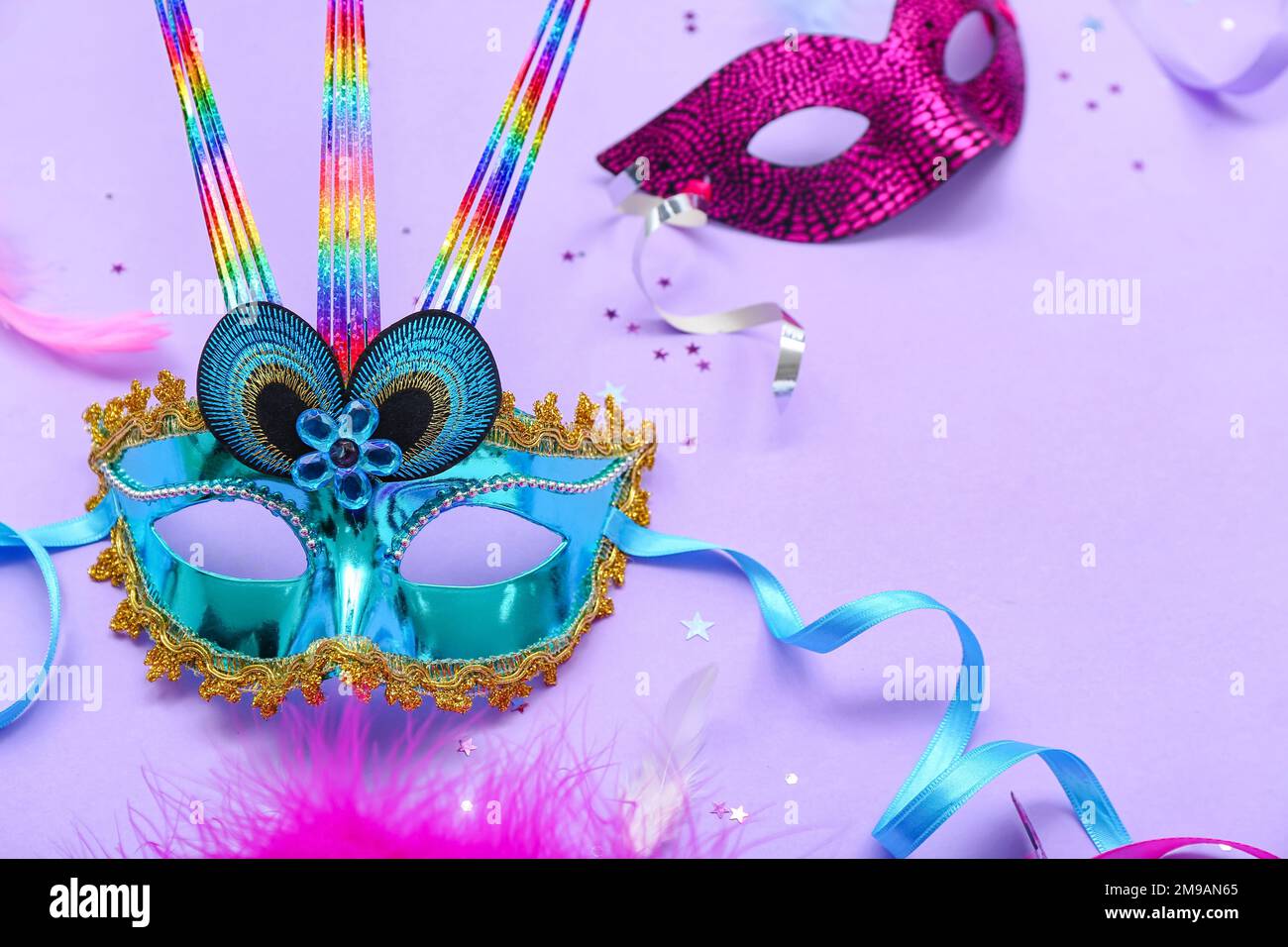 Carnival masks with confetti on lilac background Stock Photo - Alamy