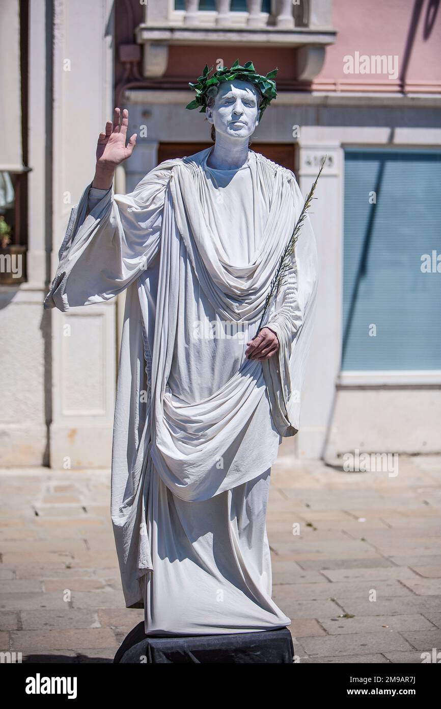 Venetian masked street performer for tourists dressed in a toga and ...