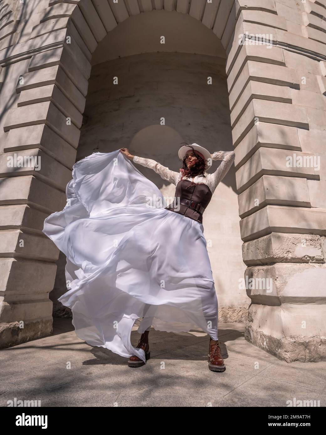 Stylish woman building city. A dancer in a long white skirt dances in ...