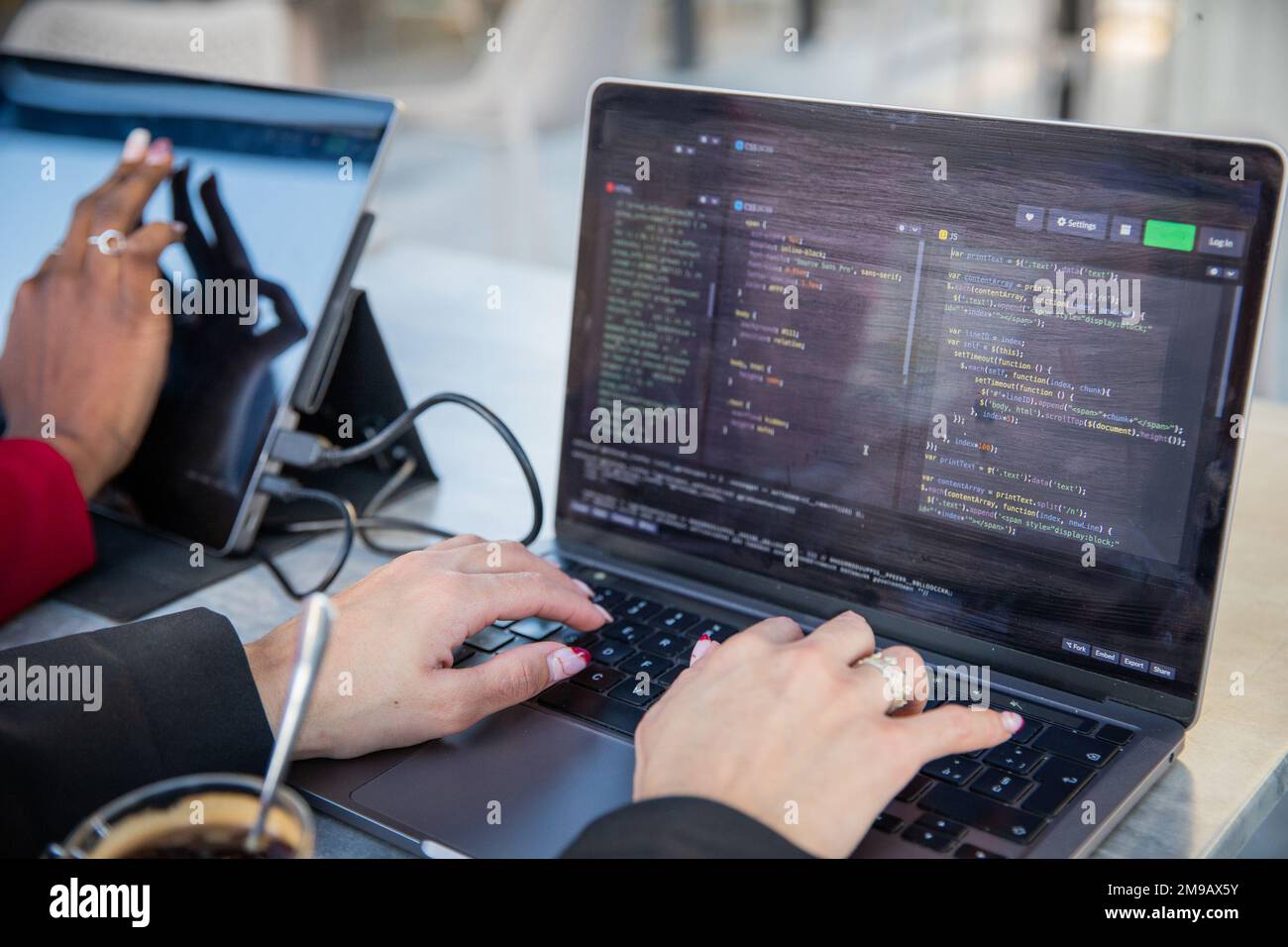 Female programmer writes some code and drinks coffee while sitting near ...