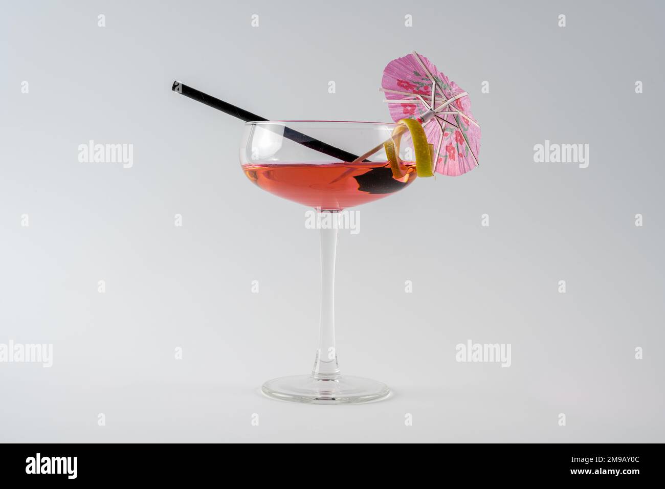 Champagne coupe with pink pina colada cocktail,umbrella lemon twist and ...