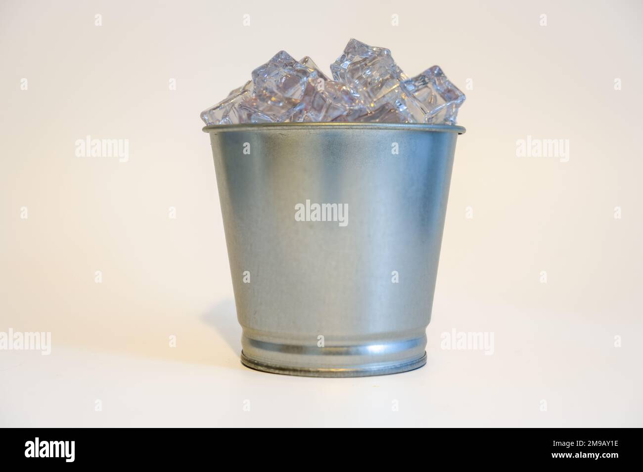Galvanised bucket full of ice cubes isolated on a white background ...