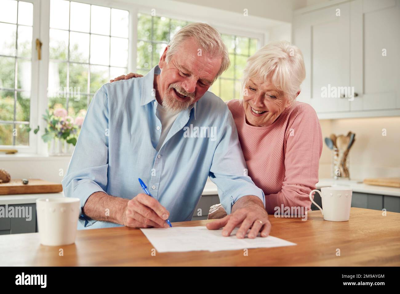Retired Senior Couple Sitting In Kitchen At Home Signing Financial ...