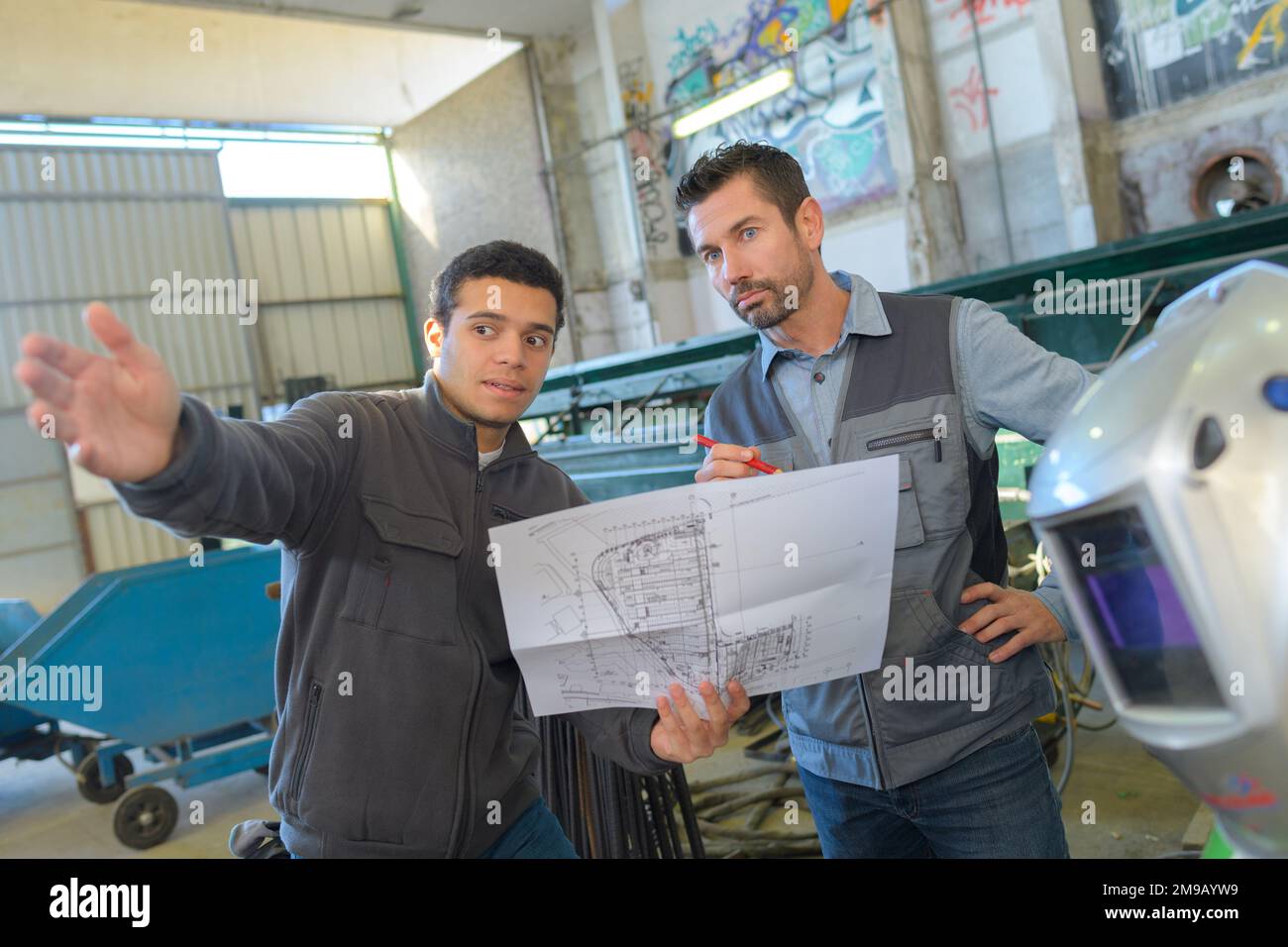 two male engineers in discussion while holding scale drawings Stock ...