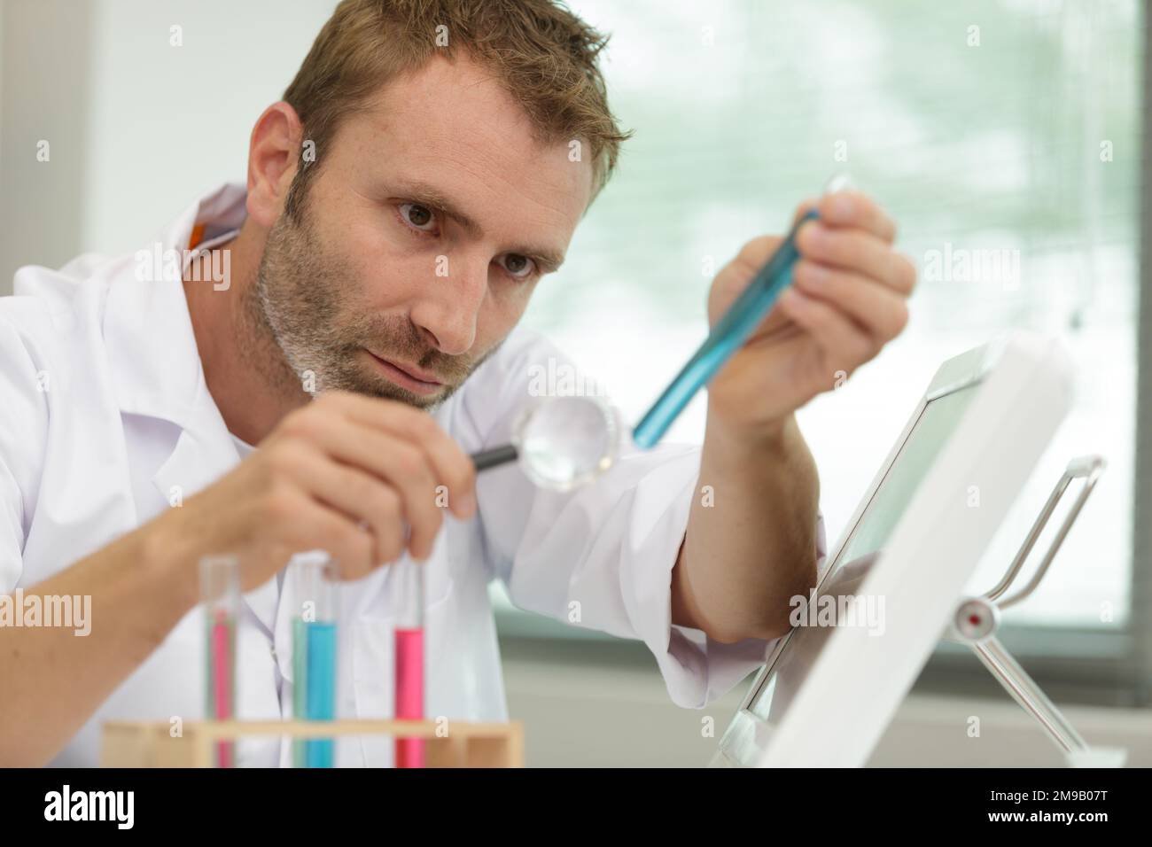 scientist looking at test tube through a magnifying glass Stock Photo ...
