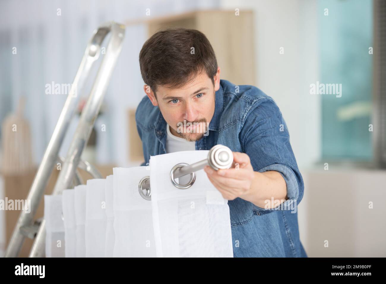 Man hanging curtain hi-res stock photography and images - Alamy