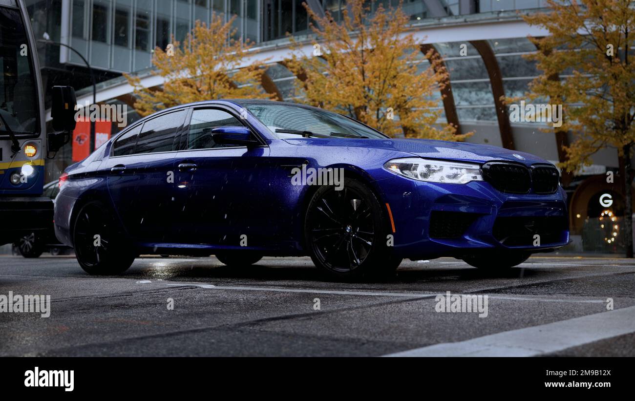 A blue big BMW M5 car driving at high speed on the road in the evening ...