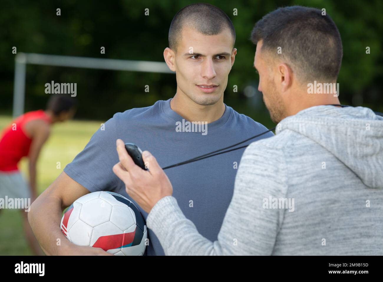 football coach holding a stopwatch and talking to player Stock Photo ...