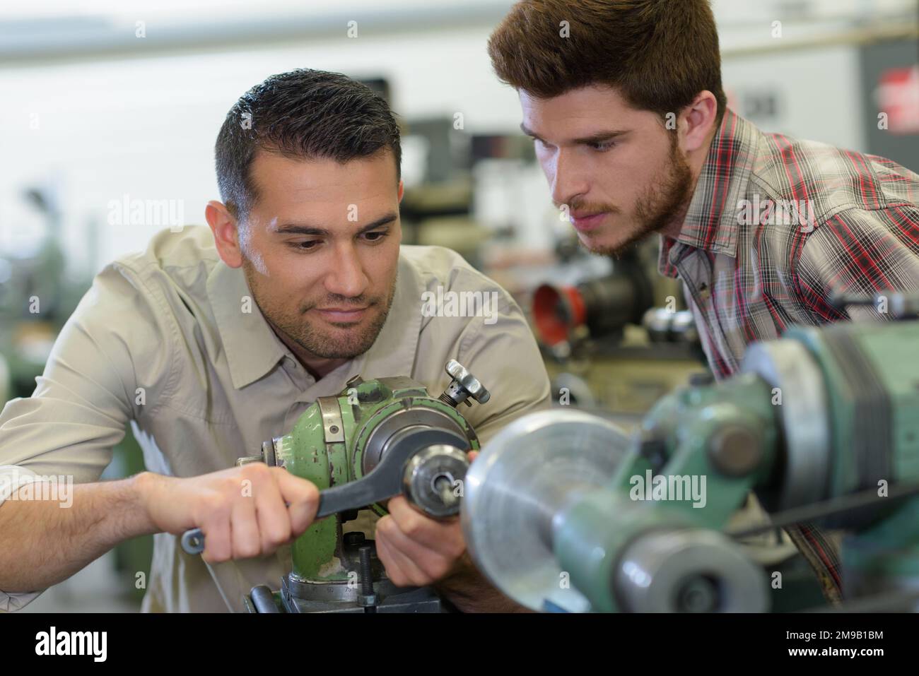 engineer showing apprentice how to use drill in factory Stock Photo - Alamy