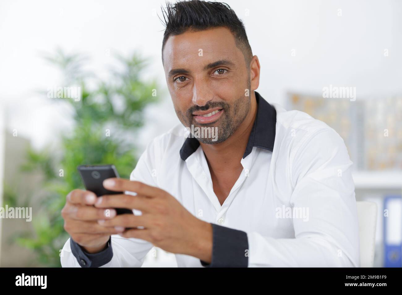 man in office wear using a phone indoors Stock Photo - Alamy