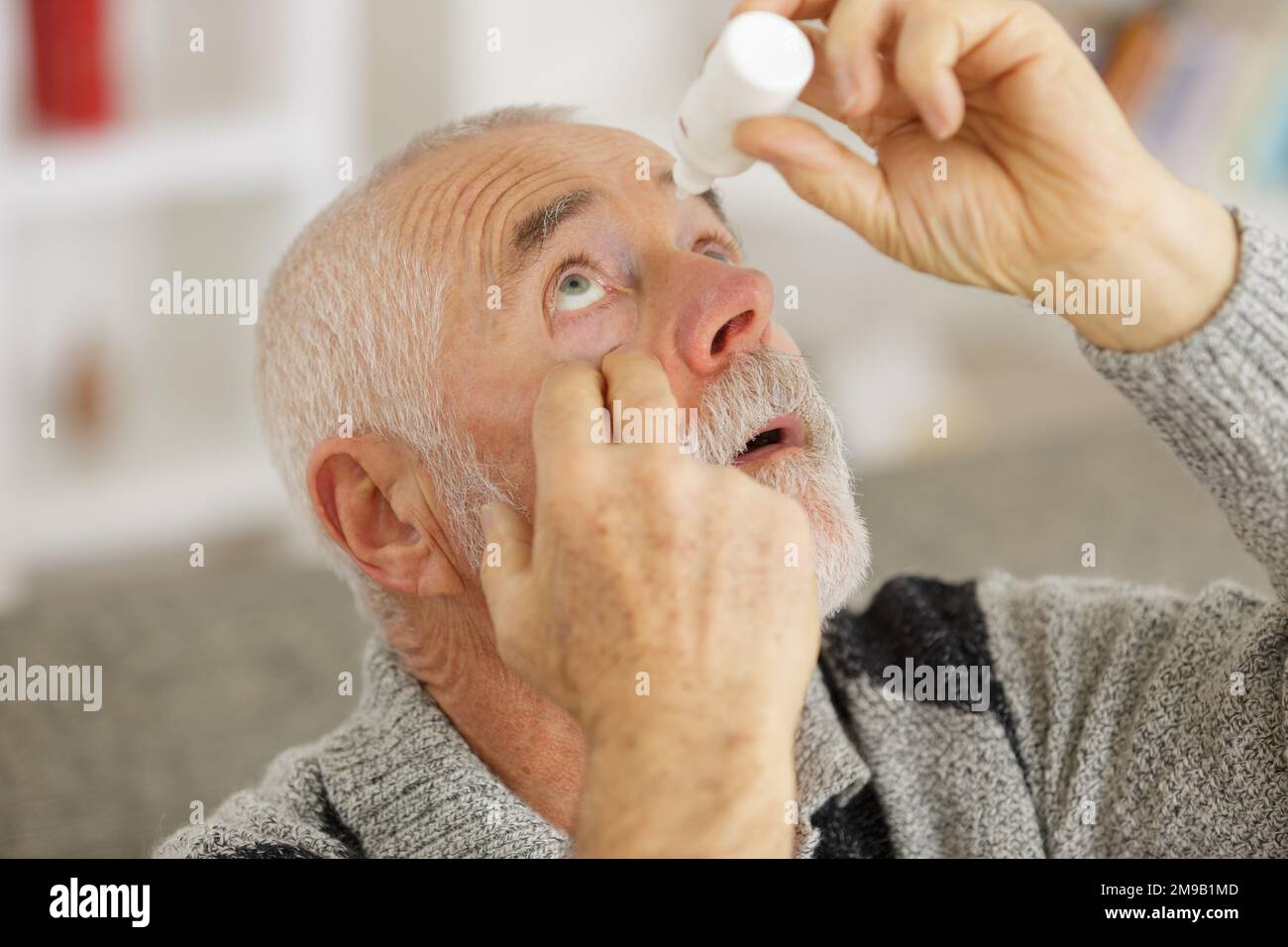 senior man dripping a red eye with eye drops Stock Photo - Alamy