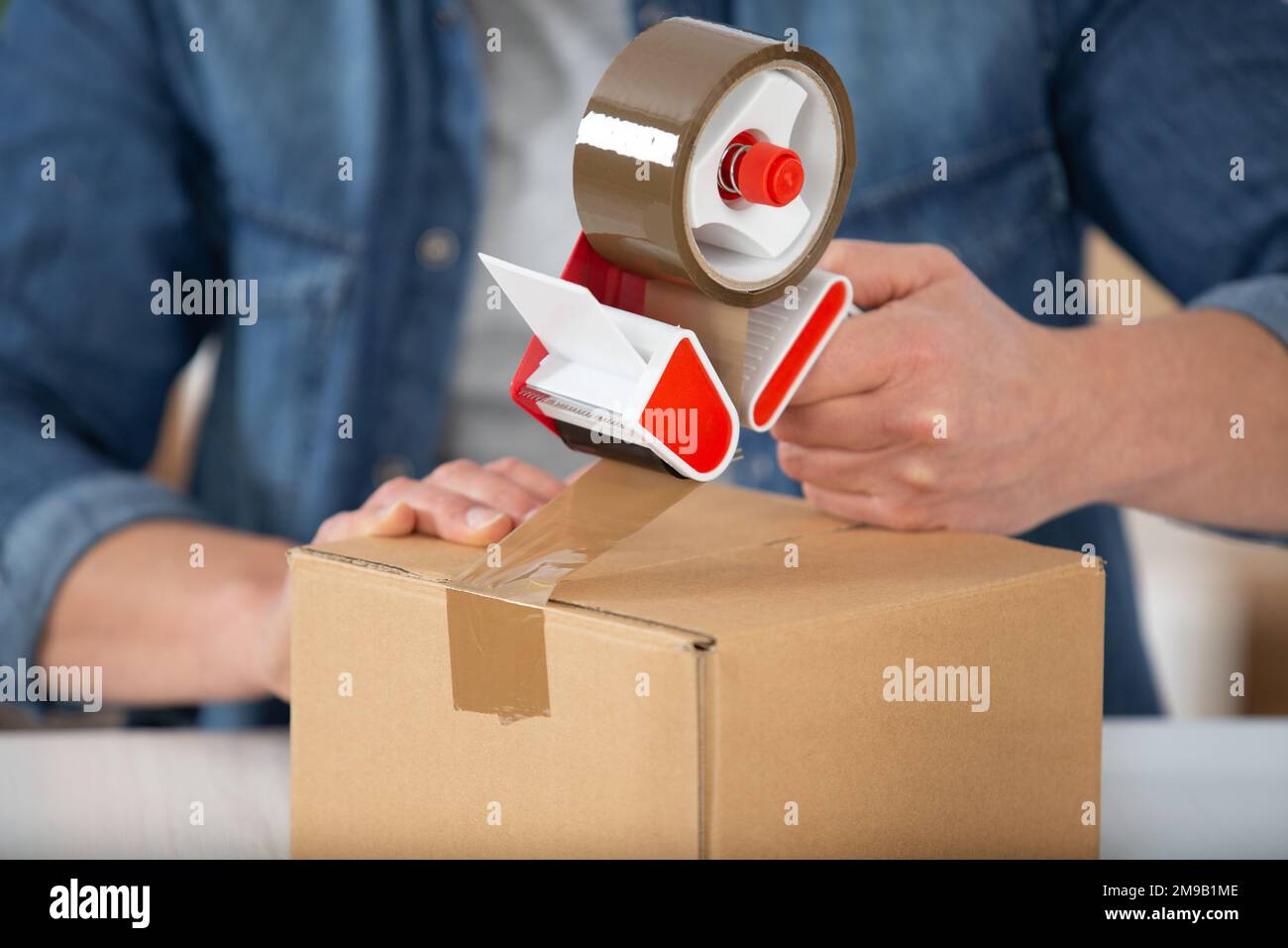 close up of person using parcel tape dispenser Stock Photo - Alamy