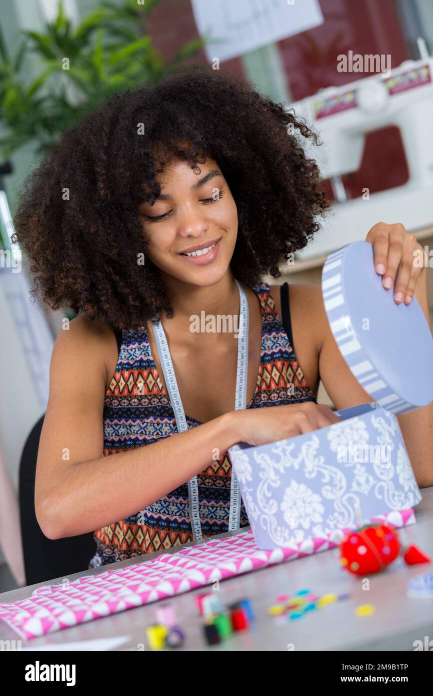 beautiful young tailor woman holding a box full of threads Stock Photo ...