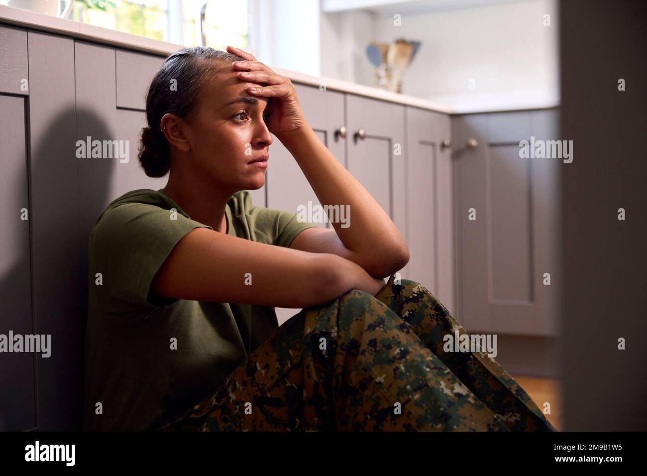 Depressed Female Soldier In Uniform Suffering With PTSD Sitting On ...