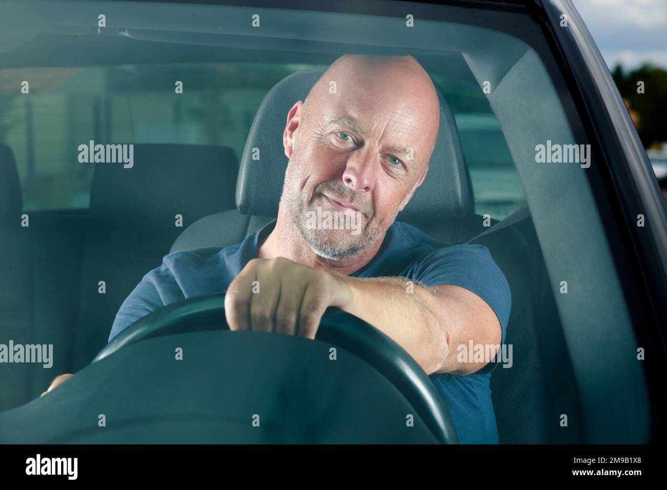 smiling handsome man driving his car and looking through window Stock ...