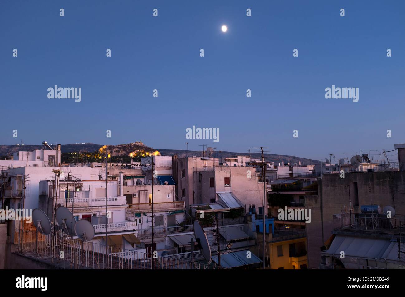 Moon rising over an Athens neighbourhood with Lycabettus Hill in the ...