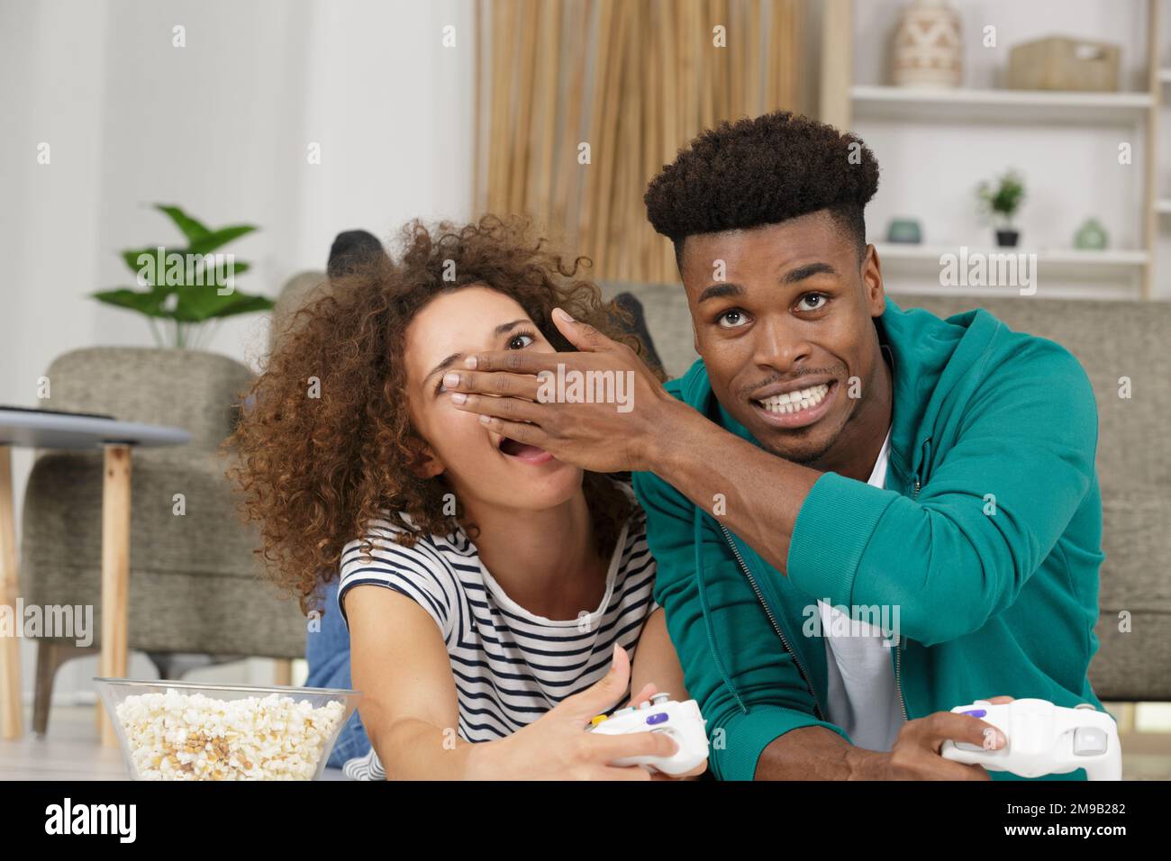 man covering females eyes during console game Stock Photo - Alamy