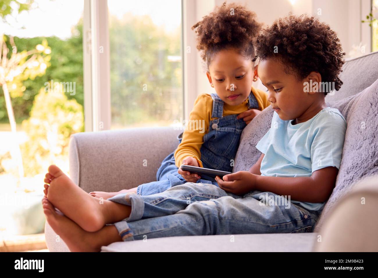 Boy And Girl Playing Handheld Computer Game Sitting On Sofa At Home ...