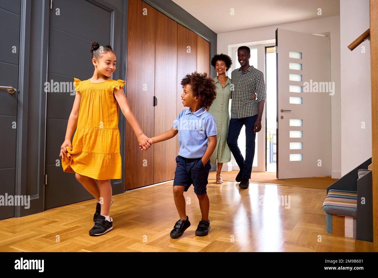 Family Coming Home After Day Out Opening Front Door And Walking Into ...