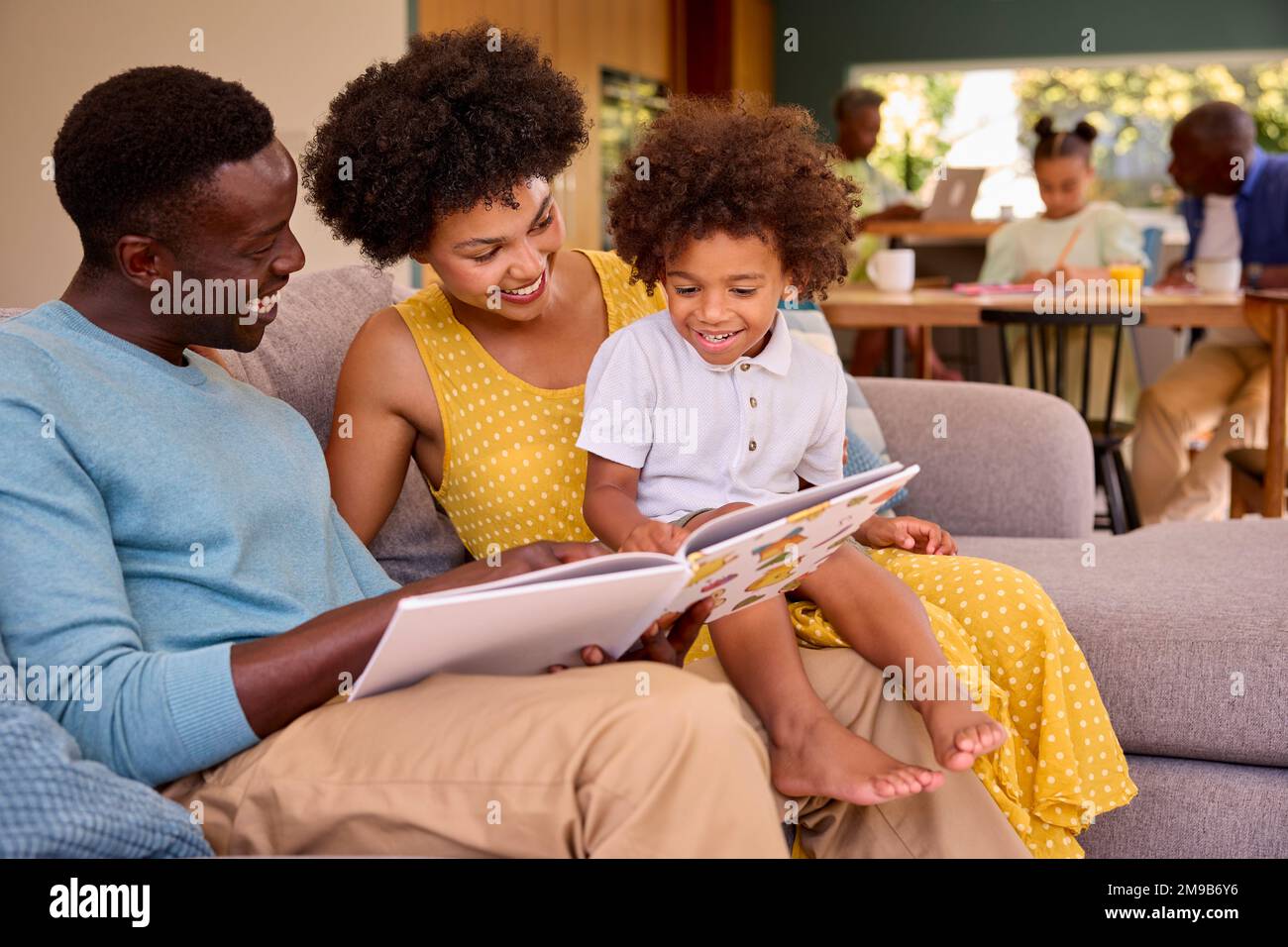 Multi-Generation Family With Parents Read Book To Son At Home As ...