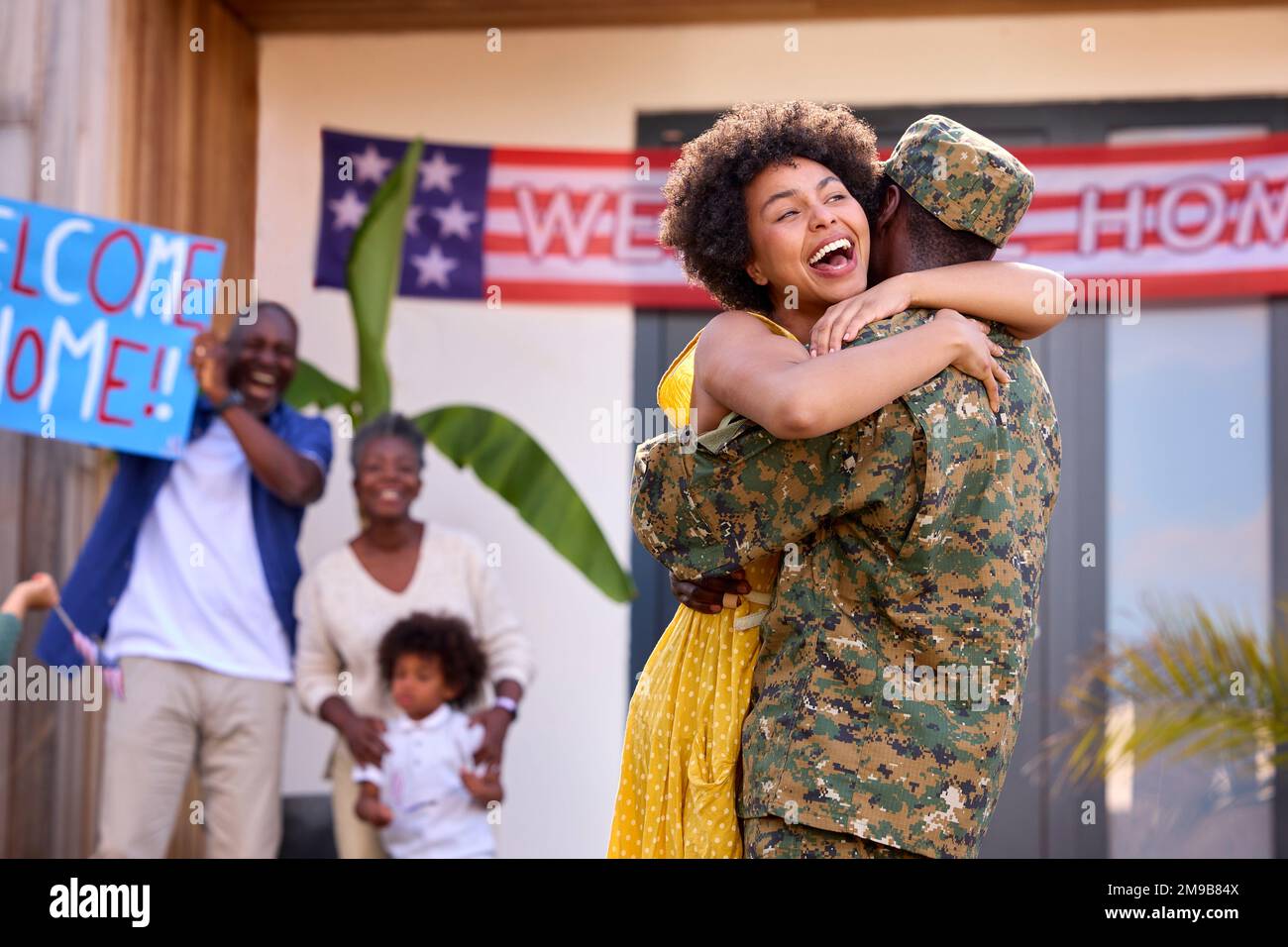 Multi-Generation Family Welcoming Army Father Home On Leave With Banner ...