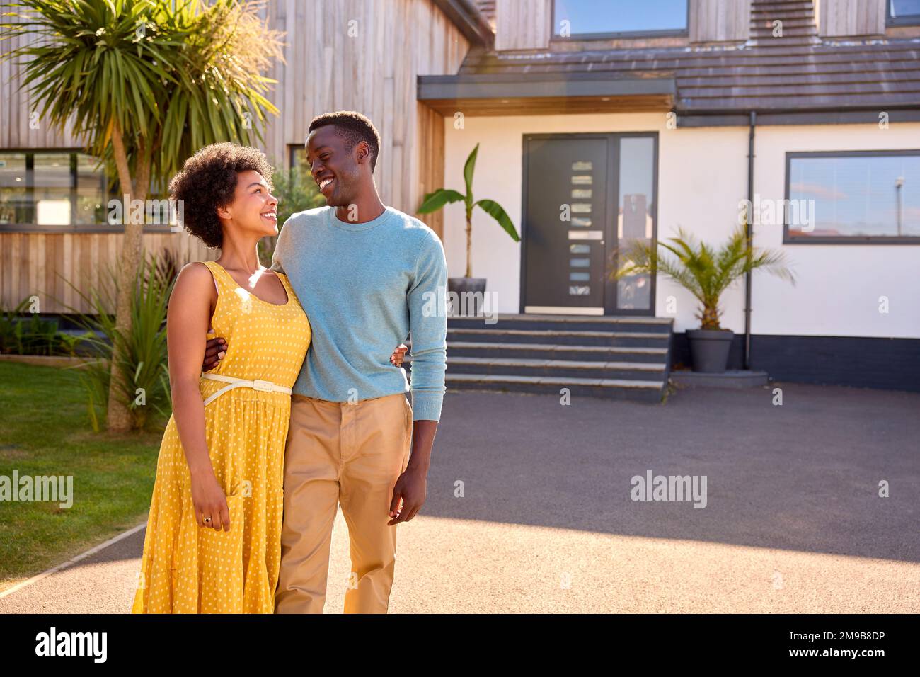 Portrait Of Couple Standing In Driveway In Front Of Dream Home Together ...