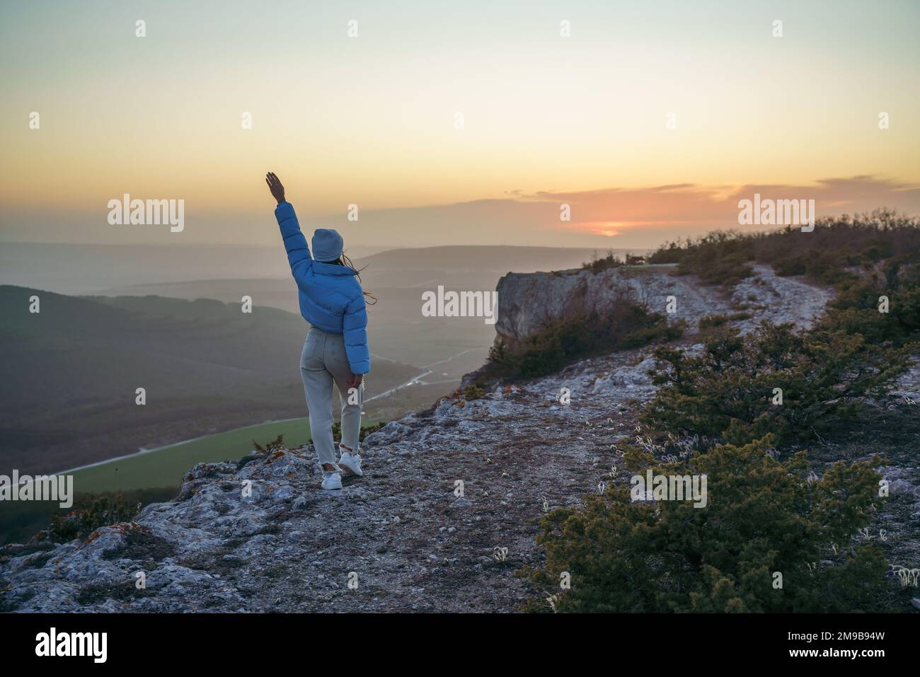 Woman hiker open arms on top of sunrise mountain. The girl salutes the ...