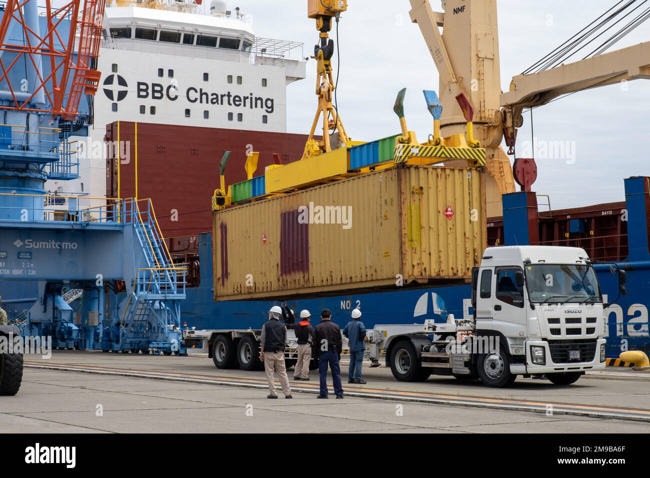Japanese dockworkers load a shipping container holding equipment ...