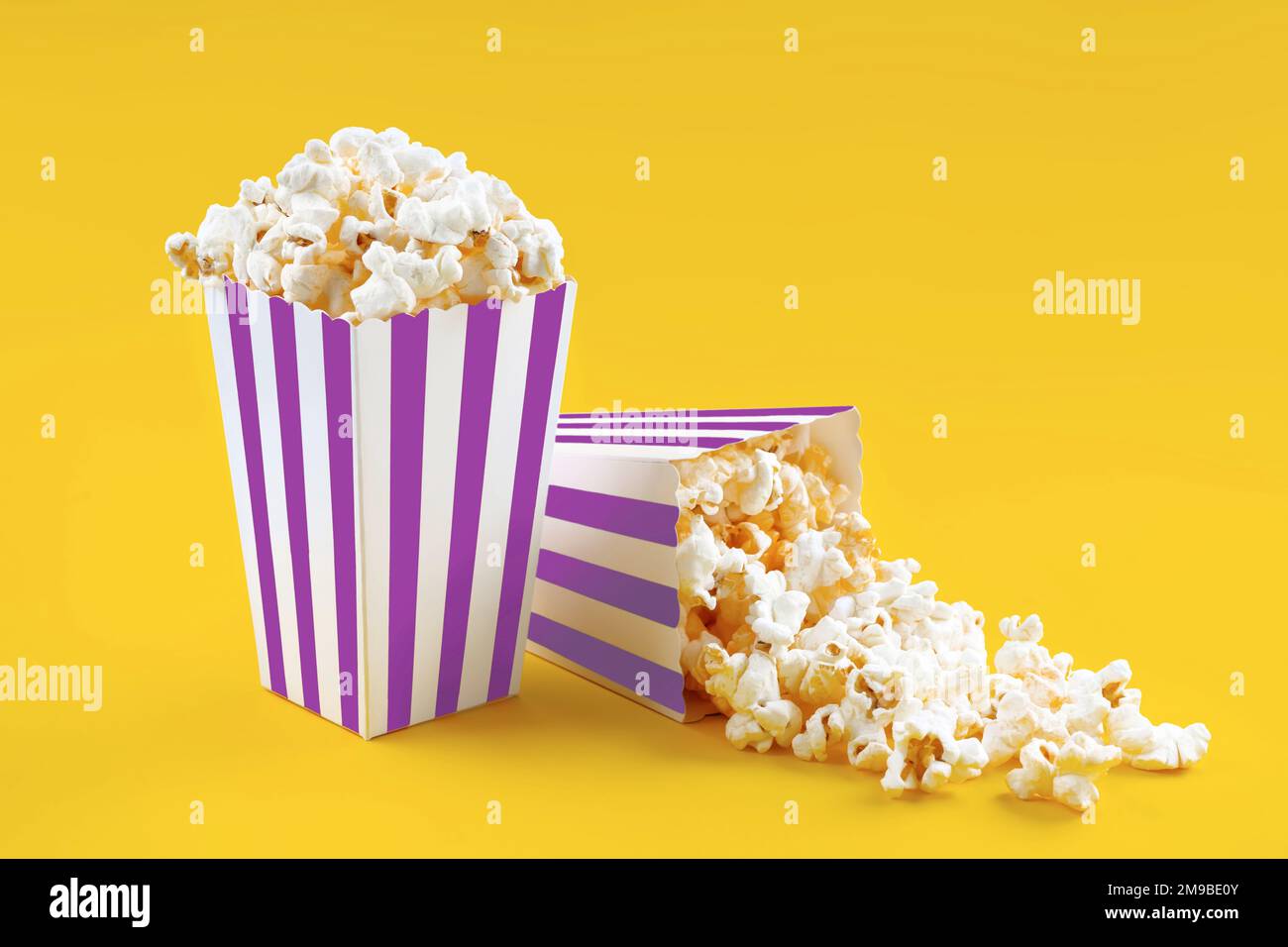 Two purple white striped carton buckets with tasty cheese popcorn ...