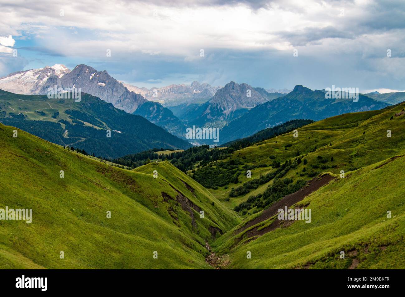 Alpine landscape with mountains and green meadows and a mountain range ...