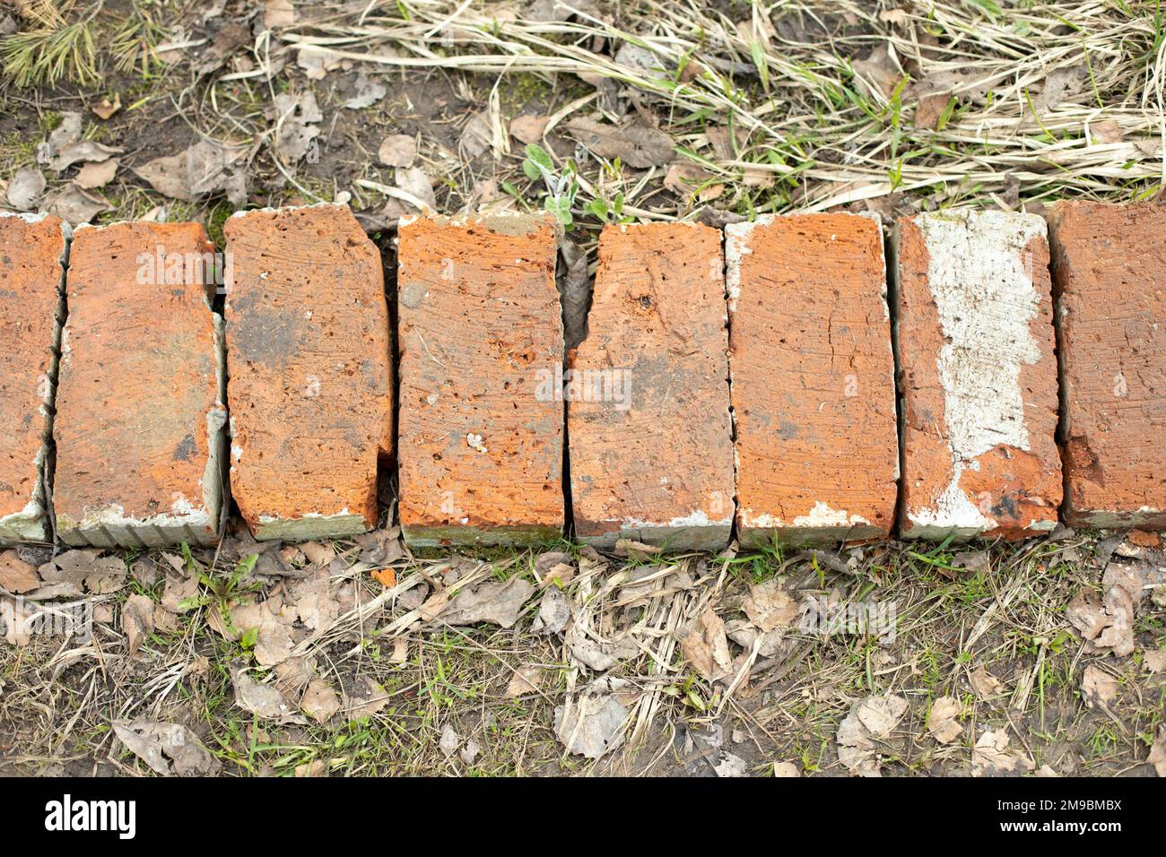 Bricks on ground. Old bricks lie in row. Stones are stacked together ...
