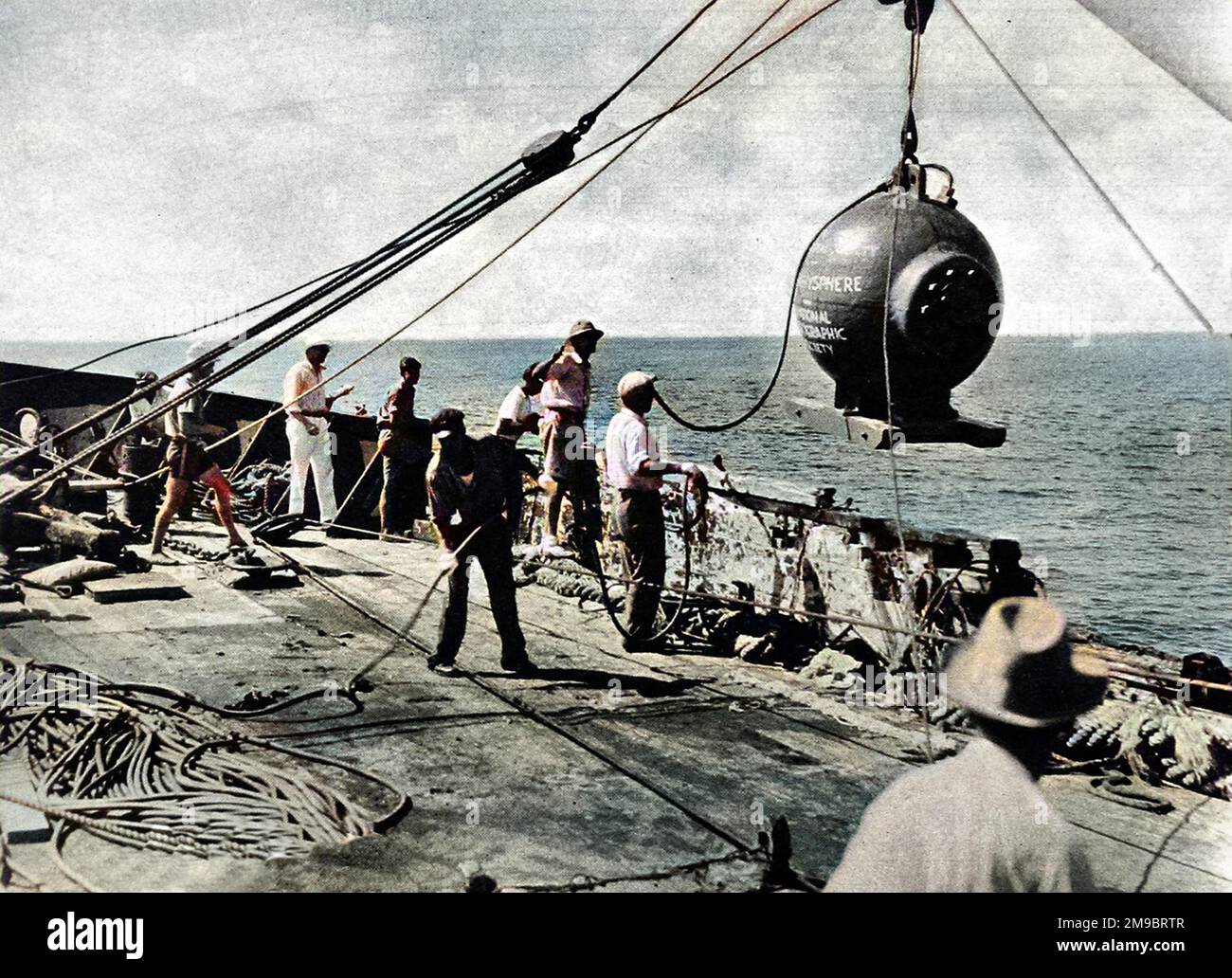Photograph of Dr. William Beebe's bathysphere being lowered into the ...