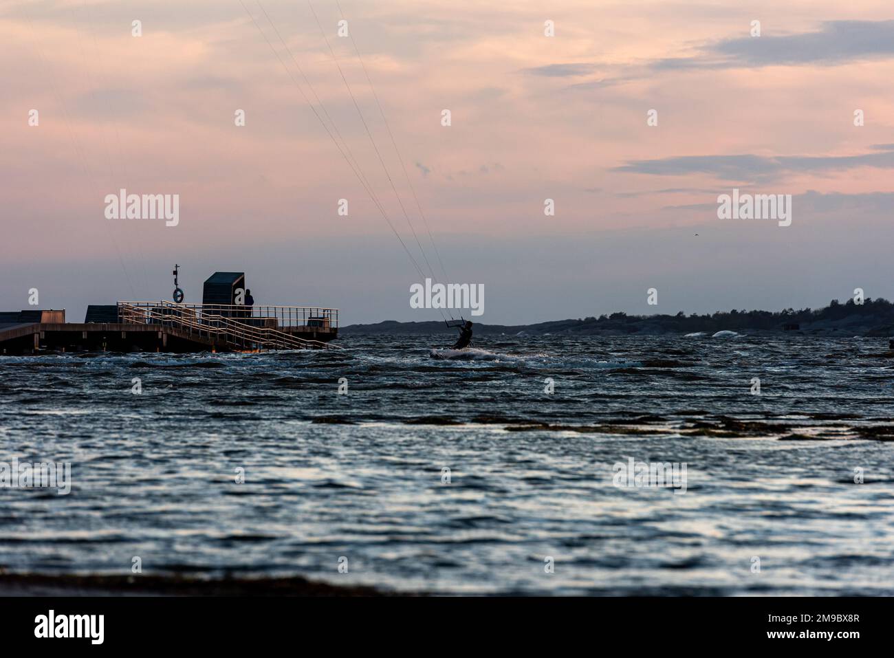 Kiteboarders kitesurfing in the sunset by a beach Stock Photo - Alamy
