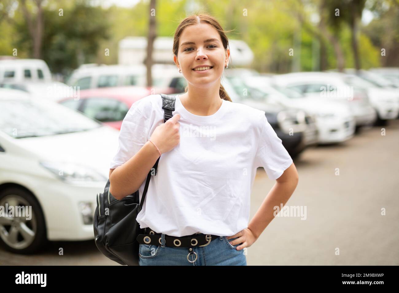 Portrait of a positive girl standing on the street near cars Stock ...
