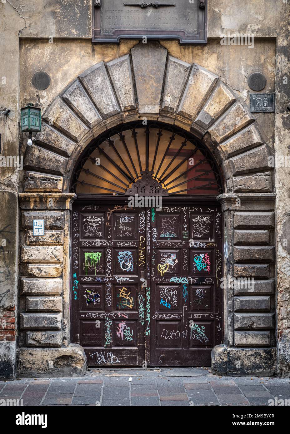 A vertical shot of an old vintage building with a graffiti painted door ...
