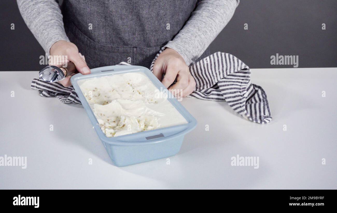 Scooping homemade coconut ice cream into a glass ice cream bowl Stock ...