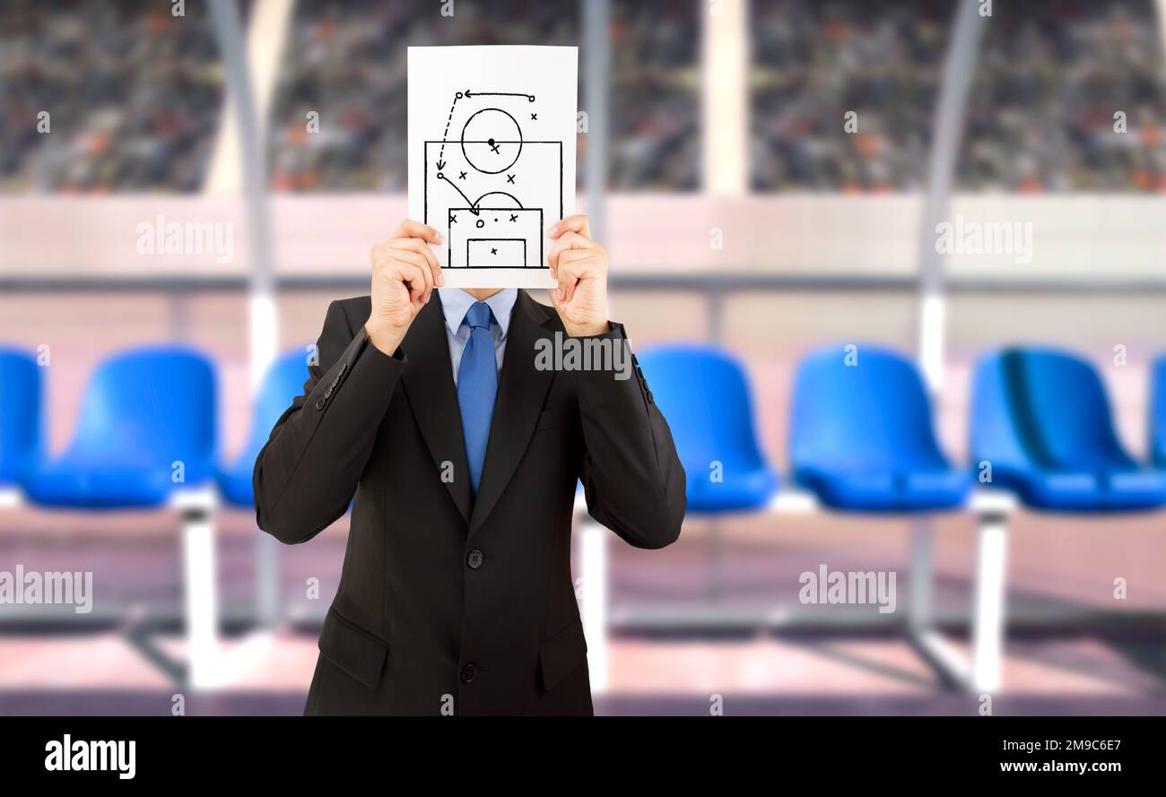 Coach holding a soccer tactics drawing in front of his face after a ...